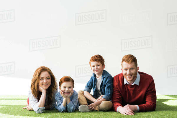 Beautiful happy redhead family lying on grass and smiling at camera on ...