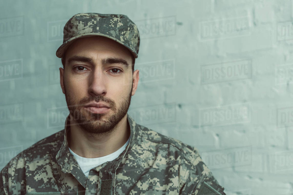 Portrait of soldier in military uniform looking at camera against white ...