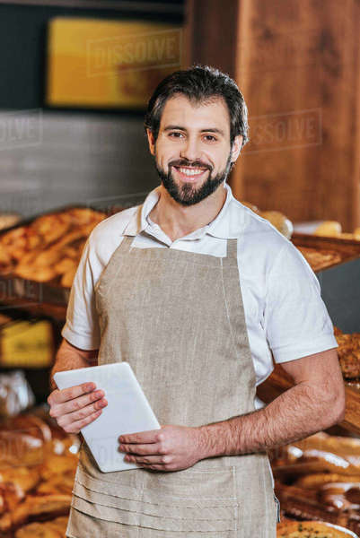 Portrait of smiling shop assistant with tablet looking at camera in ...