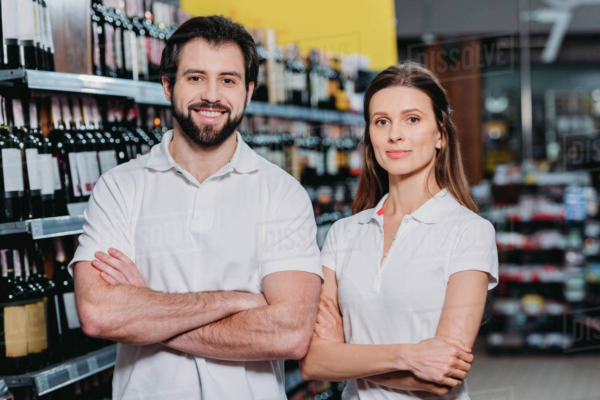 Portrait of smiling shop assistants with arms crossed in hypermarket ...