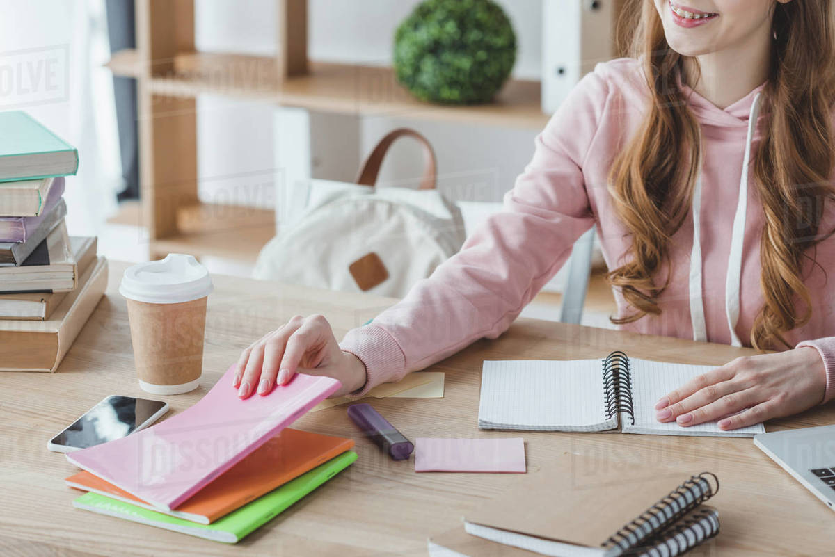 Cropped view smiling student sitting at table with copybooks - Royalty ...