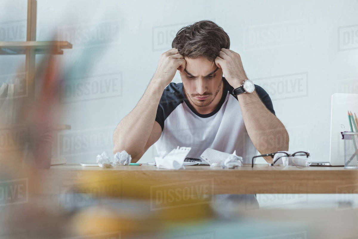 Tired student studying at table with crumpled papers - Stock Photo ...