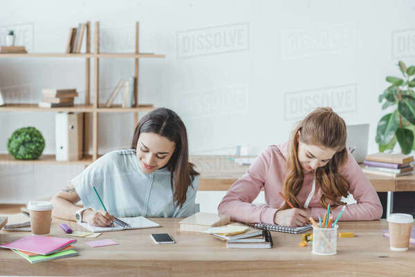 Female multiethnic students writing examination together - Stock Photo ...