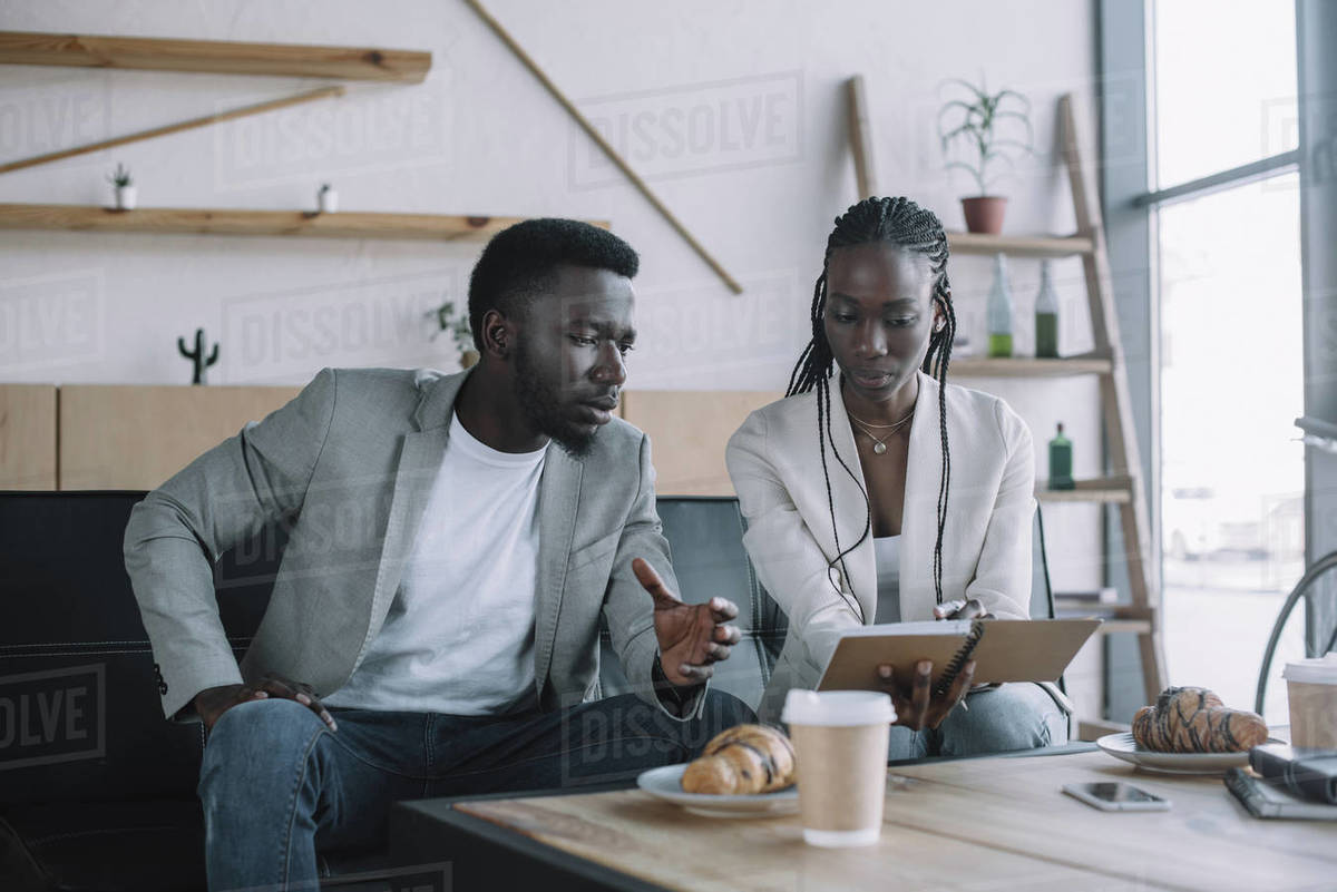 African American businesspeople discussing work during business meeting ...