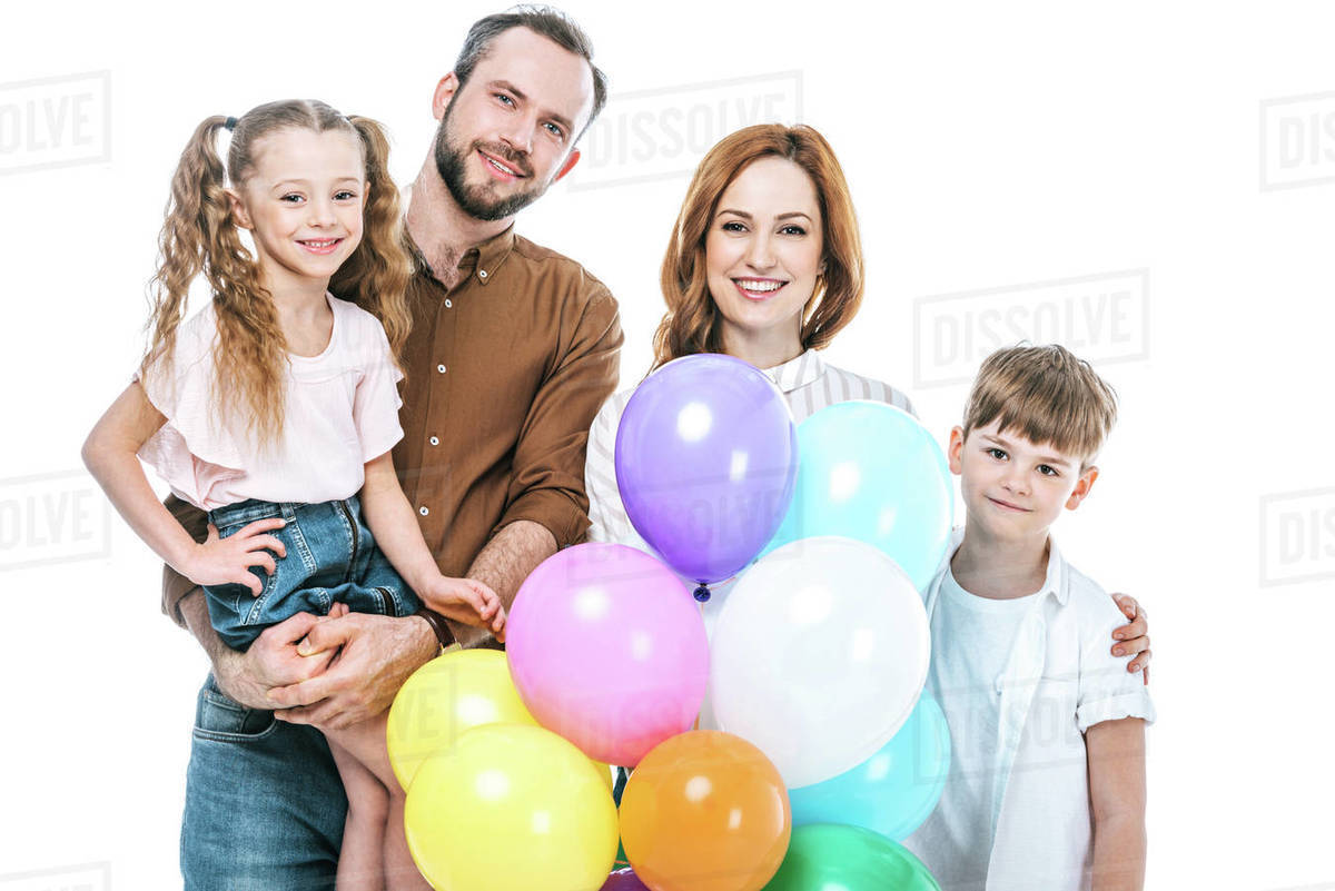 Happy family with two kids holding colorful balloons and smiling at ...