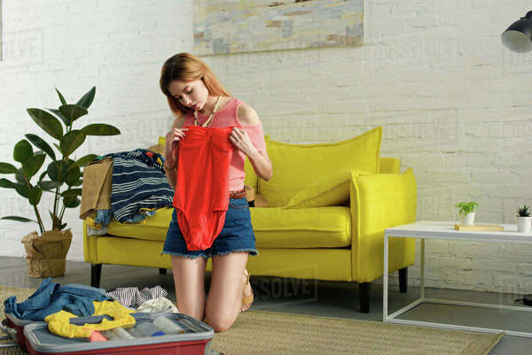 Beautiful girl packing swimsuit into travel bag for vacation - Royalty ...