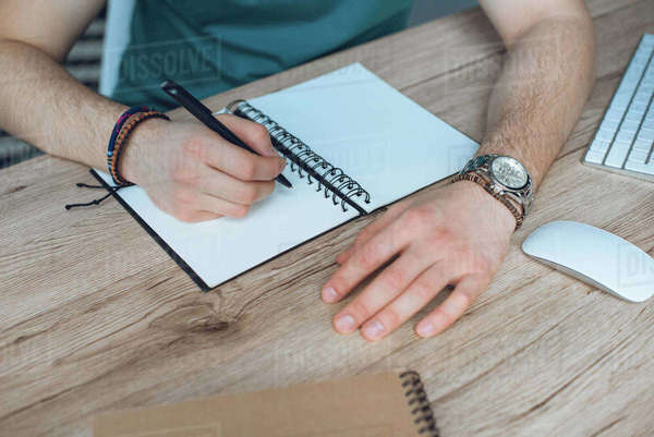 Cropped shot of young man taking notes in blank notebook - Royalty-free ...