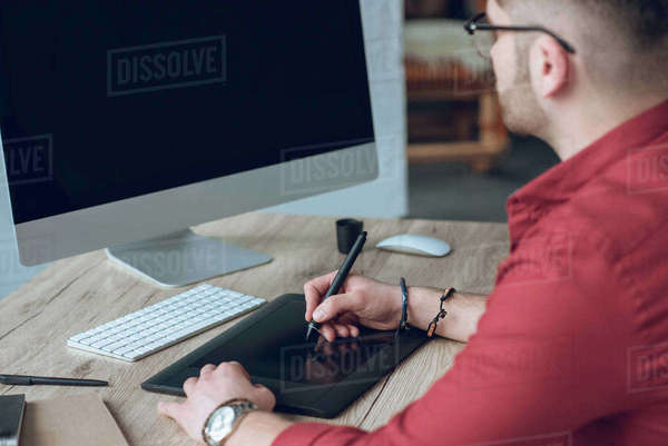 Bearded man drawing with graphic tablet by table with computer ...