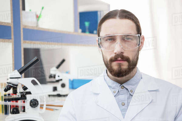 Professional male scientist in protective goggles looking at camera ...