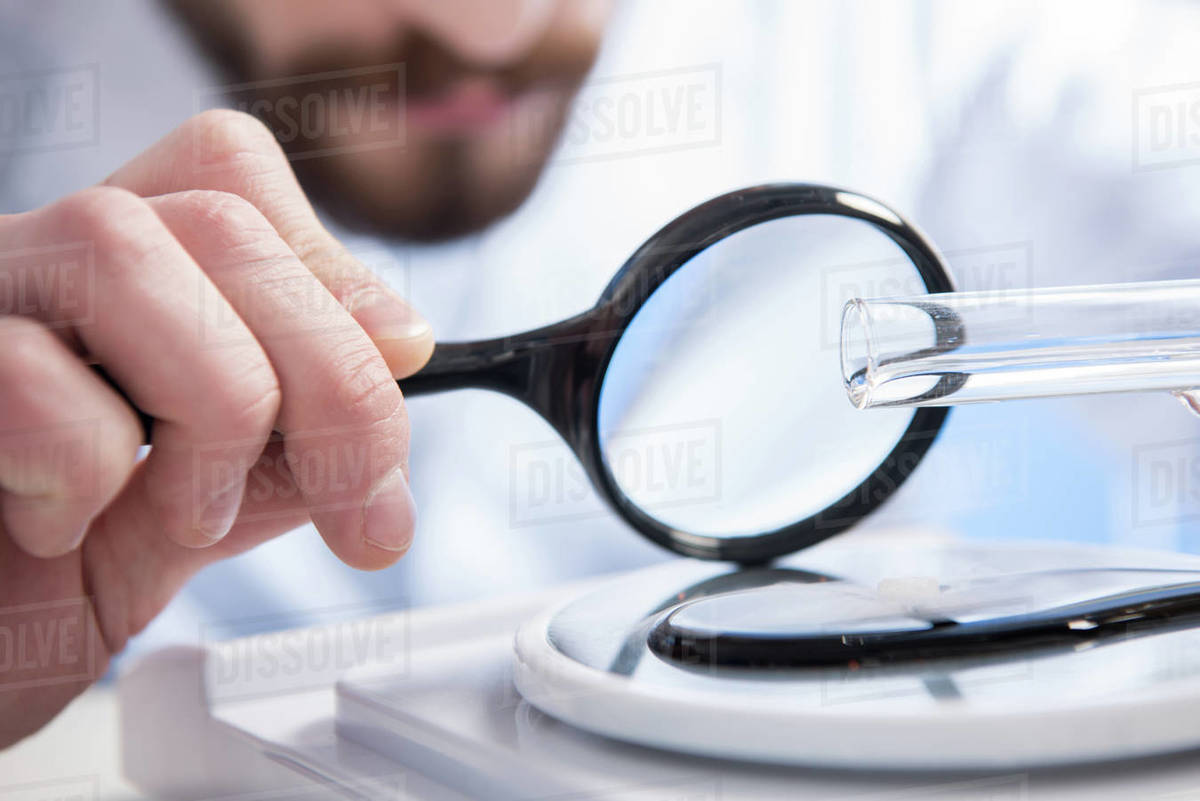 Close-up view of scientist looking at chemical sample through ...