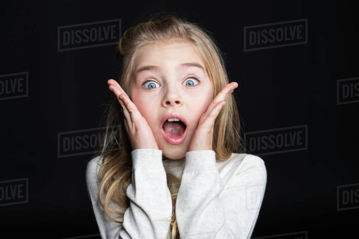 Cute shocked blonde girl looking at camera isolated on black - Royalty ...