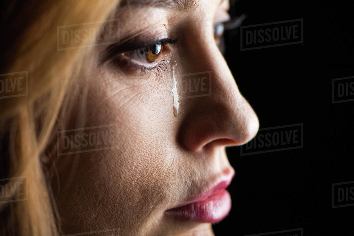 Close-up side view of young woman crying isolated on black - Royalty ...