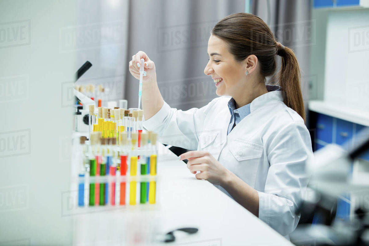 Young smiling female scientist making experiment in chemical lab ...