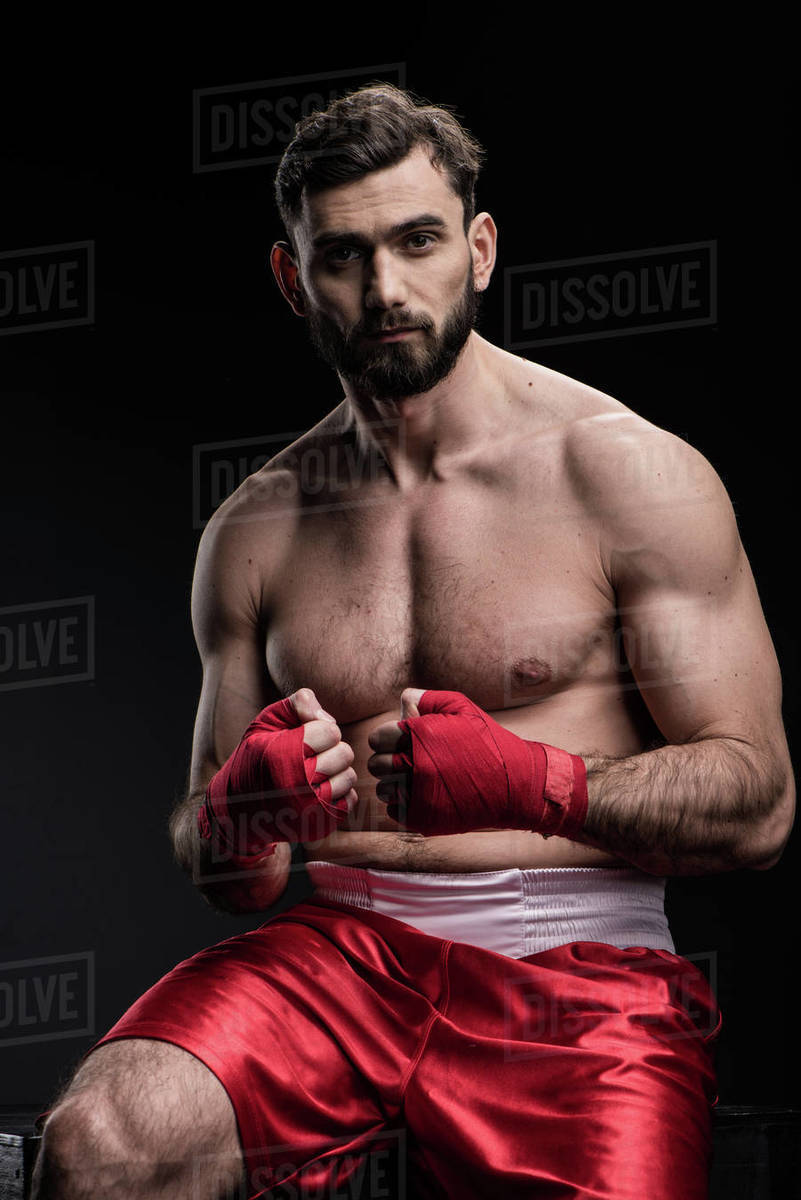 Portrait of muscular bearded boxer with wrapping hands looking at ...