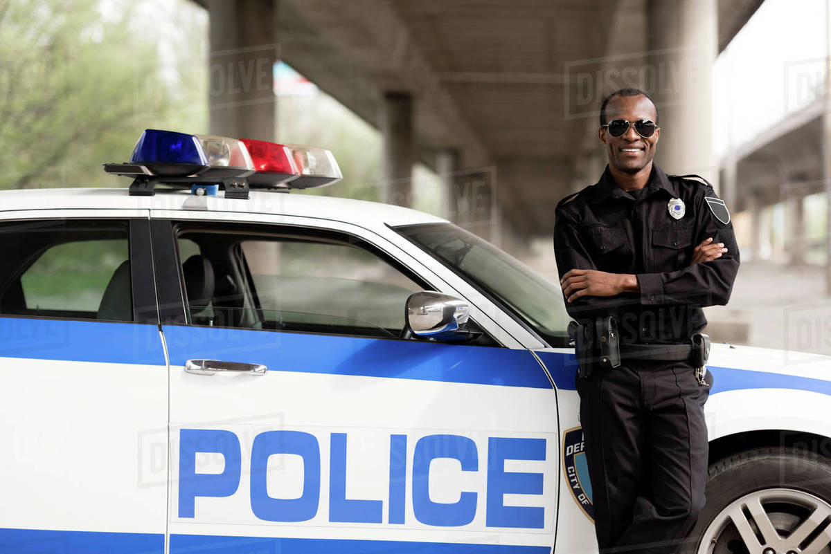 Handsome african american police officer with crossed arms leaning back ...