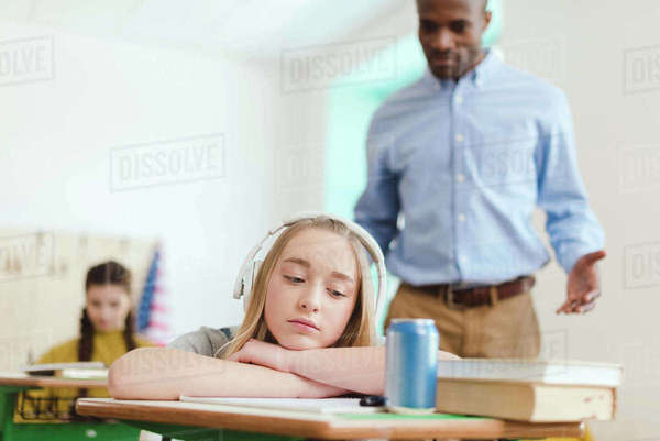 Dreamy high school teenage student listening music in headphones with ...