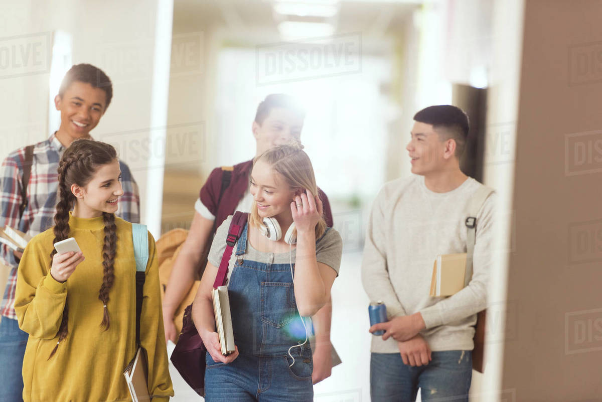 Group of high school classmates spending time at school corridor ...