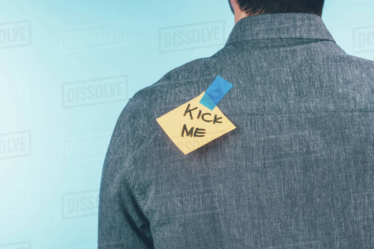Back view of man with note on sticky tape with kick me lettering on ...