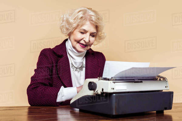 Stylish senior woman using typewriter at table - Royalty-free Stock ...