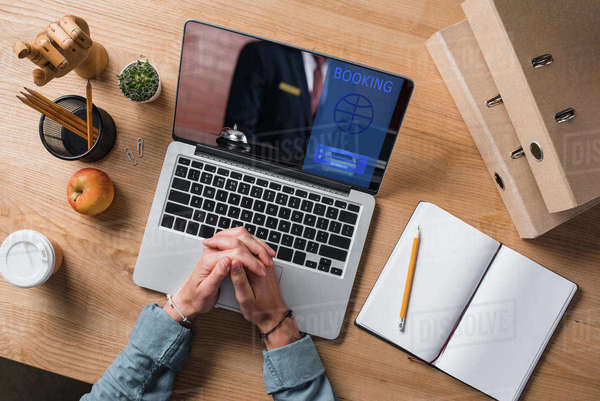 Cropped shot of businessman sitting at workplace with laptop, booking ...