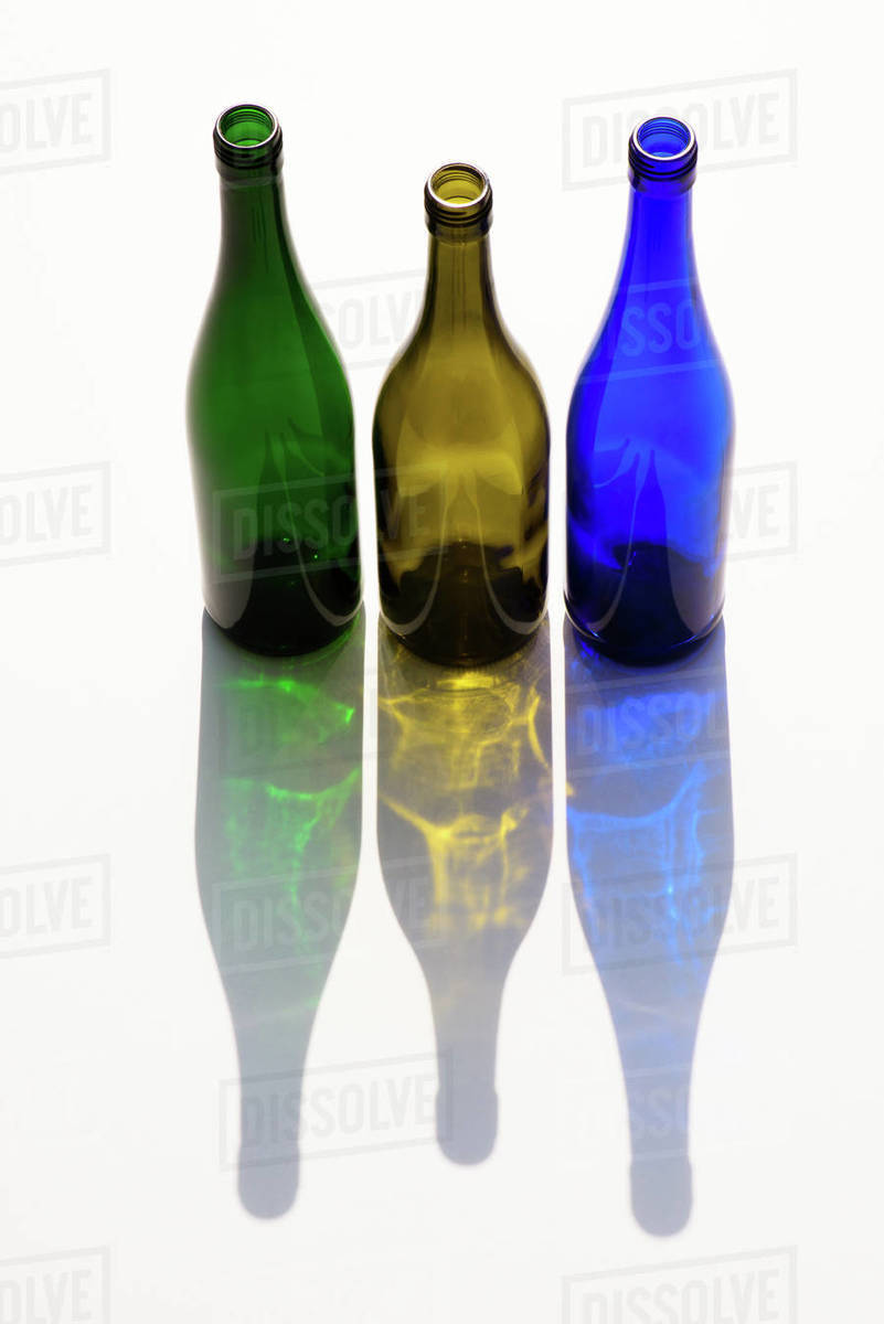 Close up view of empty colorful glass bottles with shadows on white ...