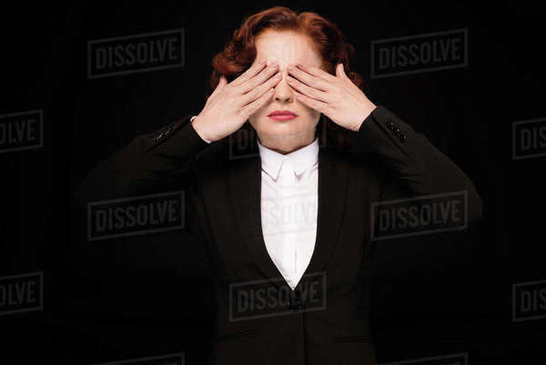 Half-length shot of businesswoman in a suit covering her eyes with her ...