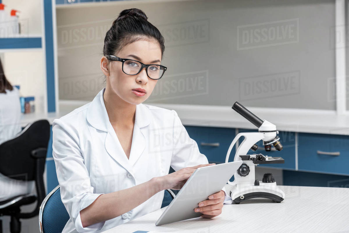 asian scientist in lab coat with microscope and digital tablet working ...