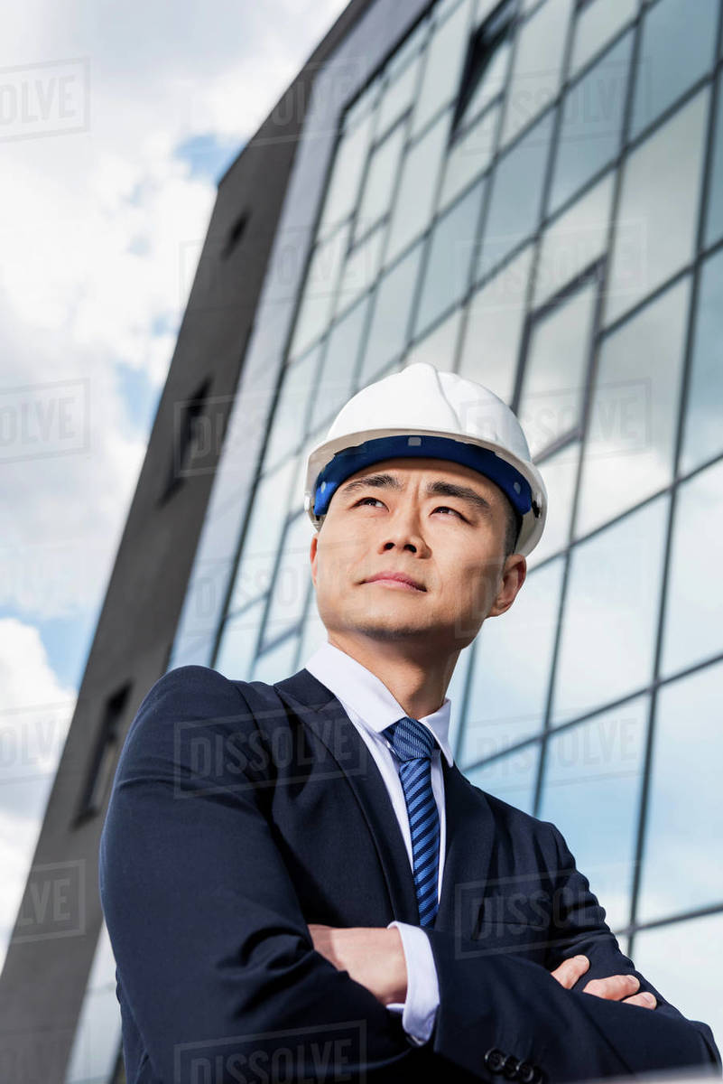 Low angle view of professional architect in hard hat looking away ...