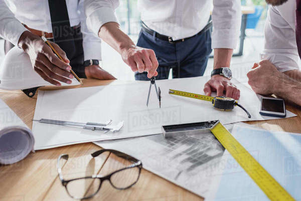 partial view of team of architects working on plan together in modern ...