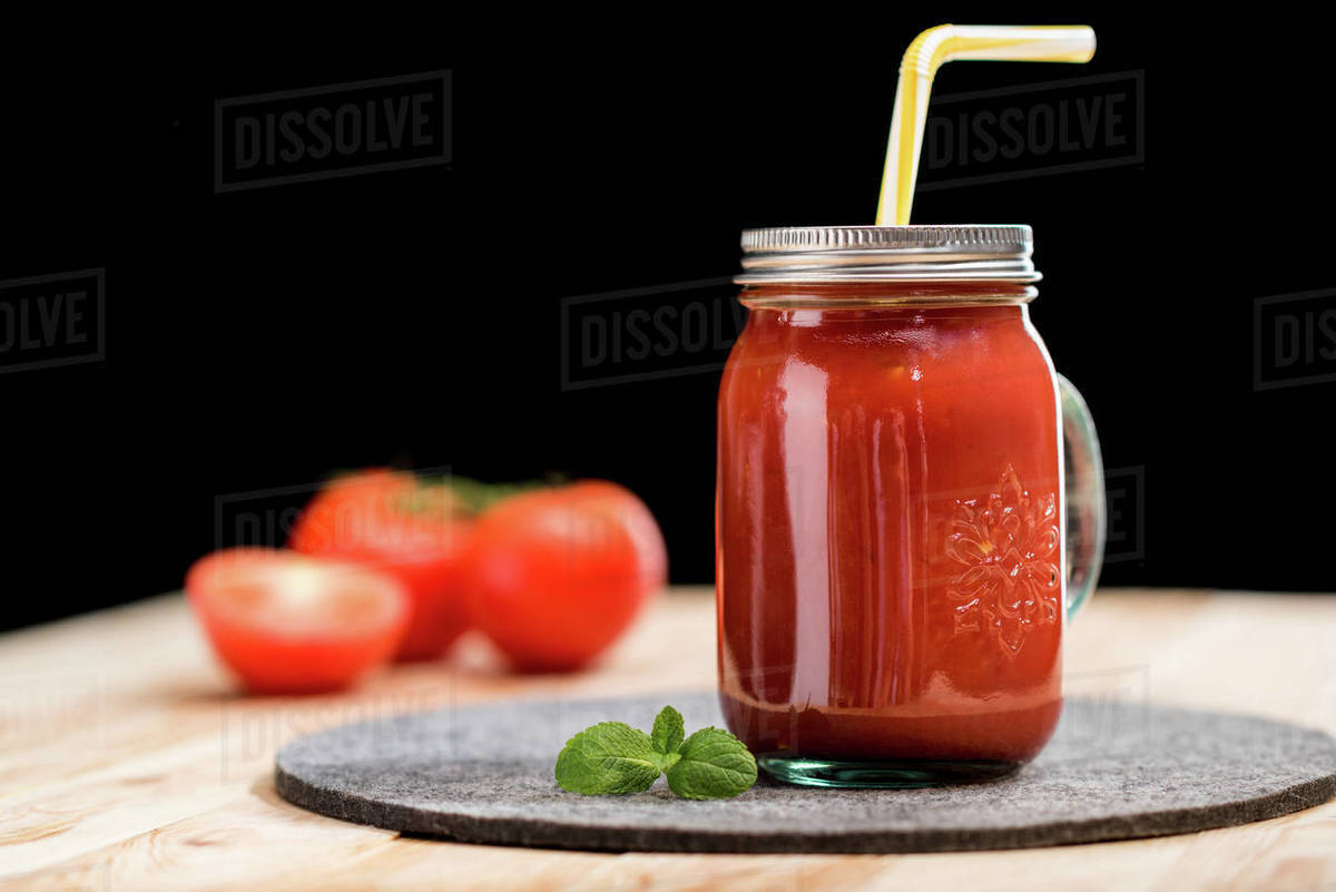selective focus of fresh tomato smoothie with basil leaves and straw on ...