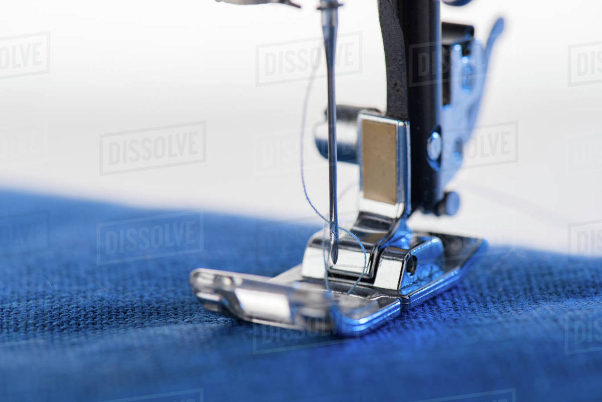 Close-up view of working sewing machine sewing blue fabric - Royalty ...