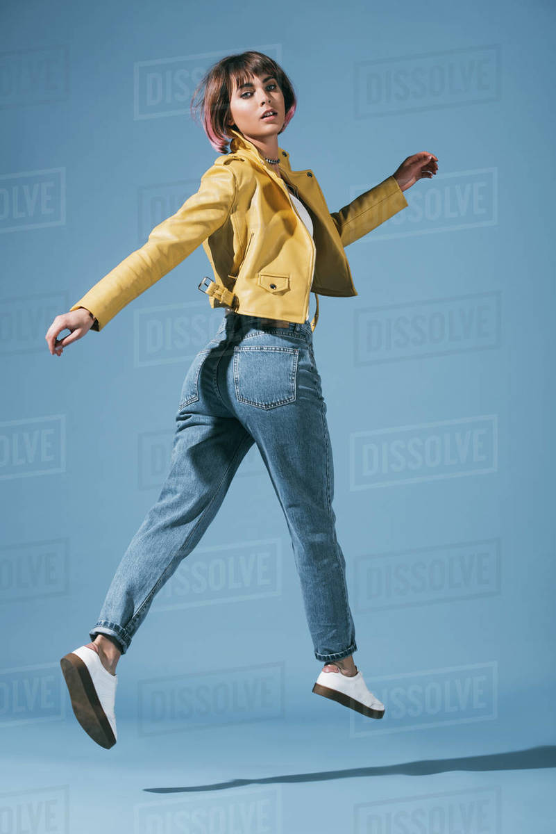 Stylish girl jumping and looking at camera on blue - Royalty-free Stock ...