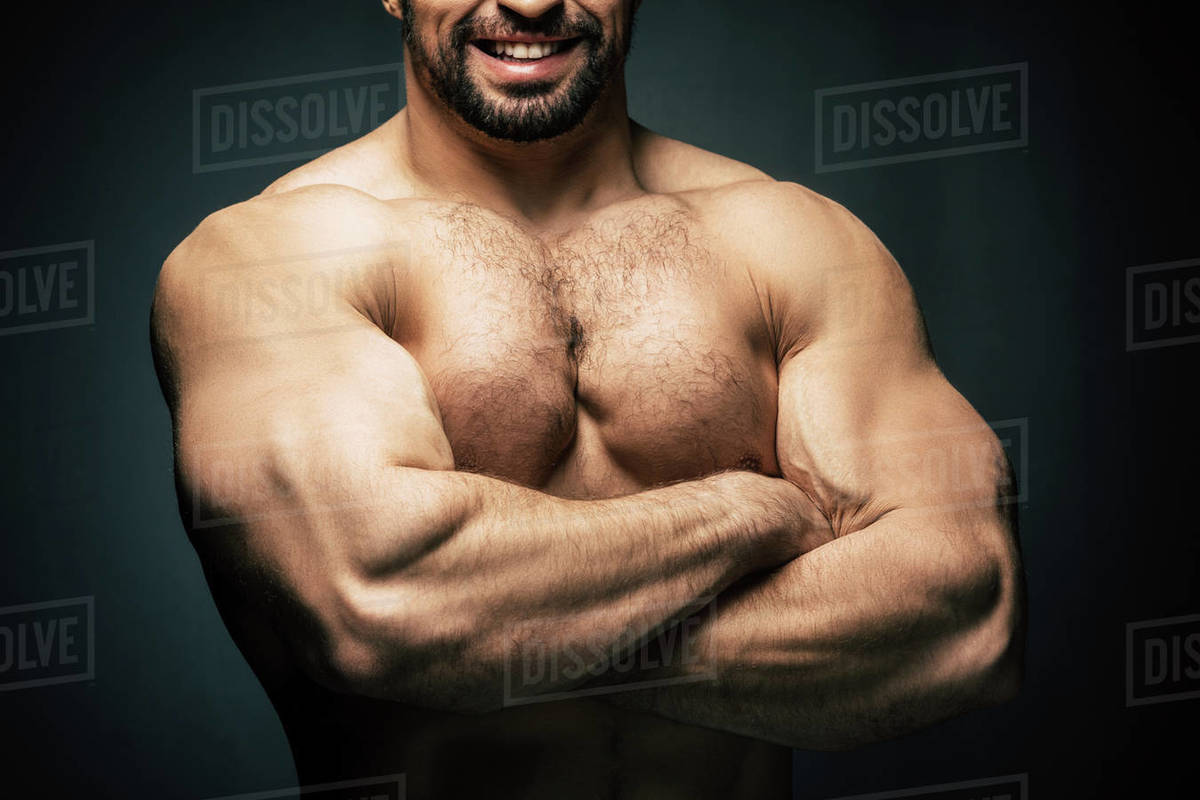 Cropped shot of shirtless sportive man with arms crossed showing ...