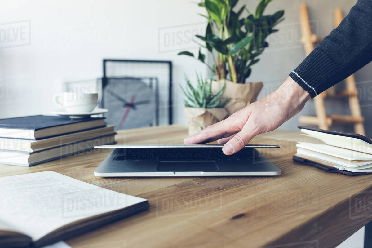 Human hand holding laptop at workplace in home office - Stock Photo ...