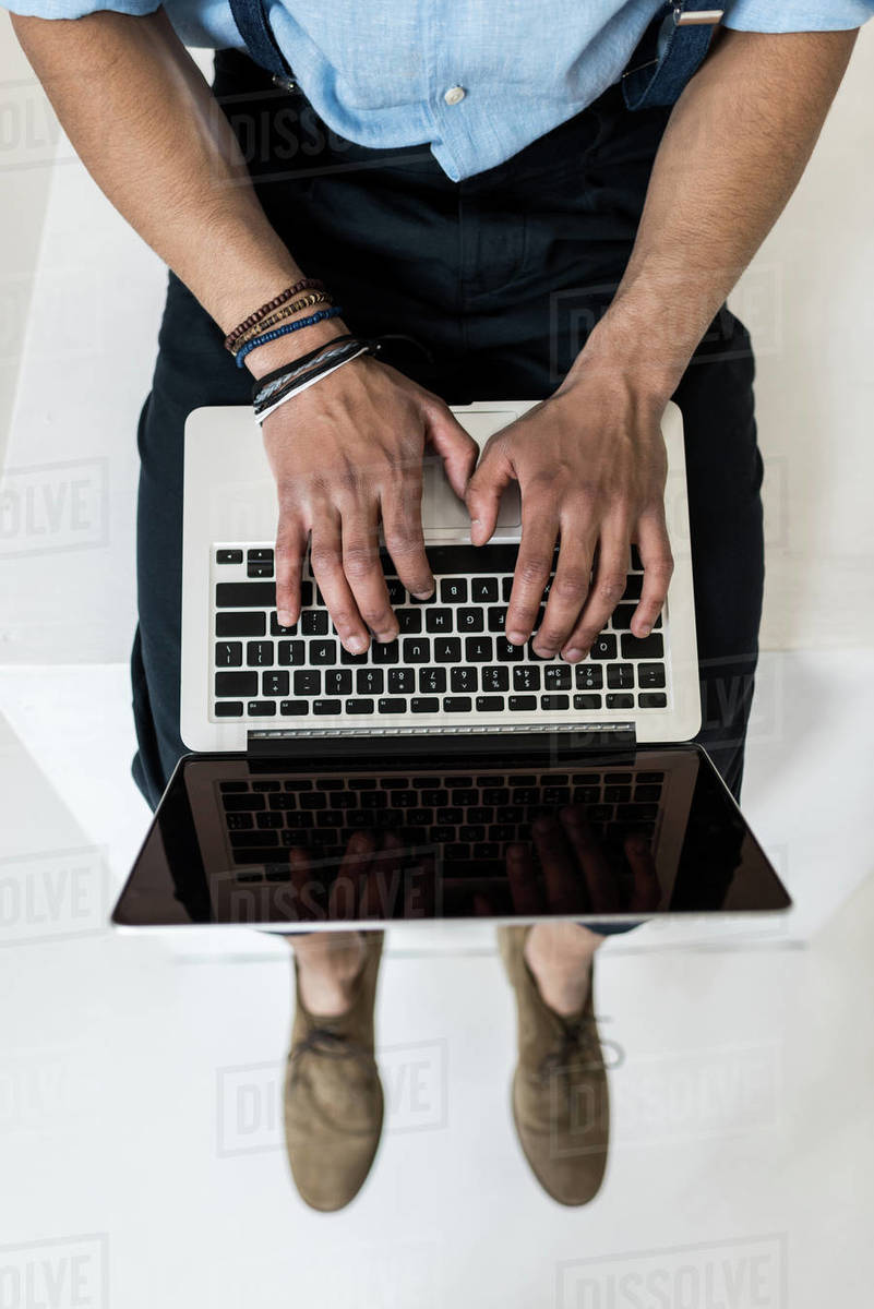Cropped shot of young man using laptop with blank screen on grey ...