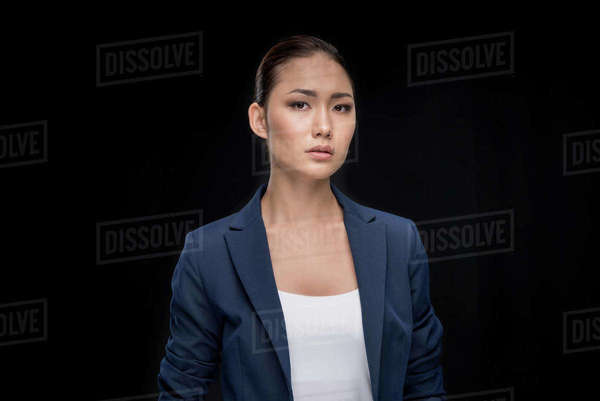 Portrait of serious businesswoman in formalwear looking at camera ...