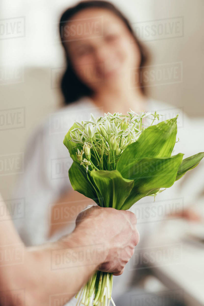 Cropped shot of man presenting bouquet of flowers to his girlfriend at ...