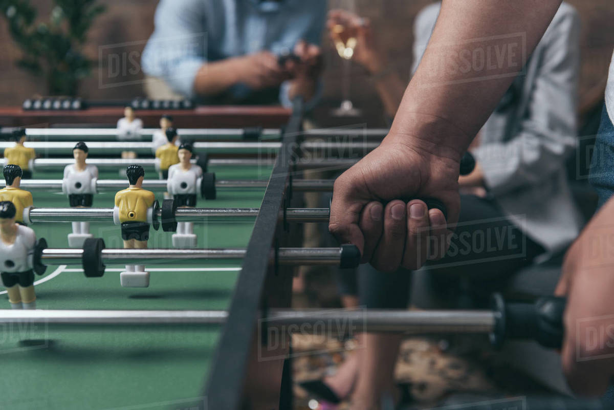 Close-up partial view of young people playing foosball indoors ...