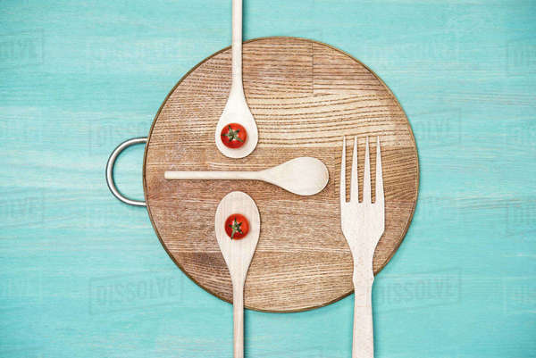 Top view of wooden cooking utensils with tomatoes in form of face on ...