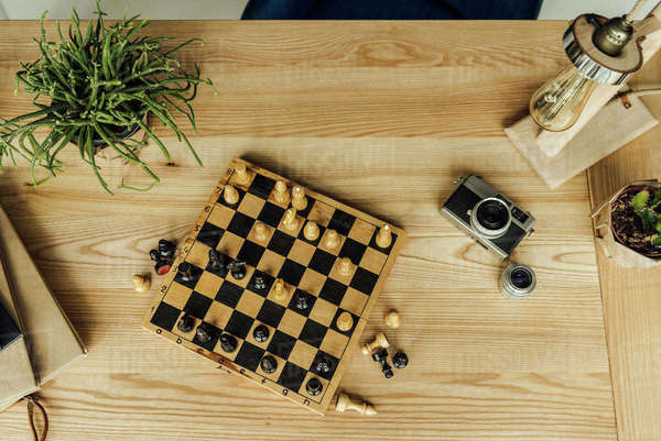 Top view of chess board with chess pieces, vintage camera and potted ...