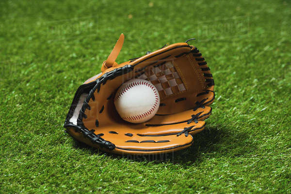 Close up of professional baseball glove with ball on green grass ...