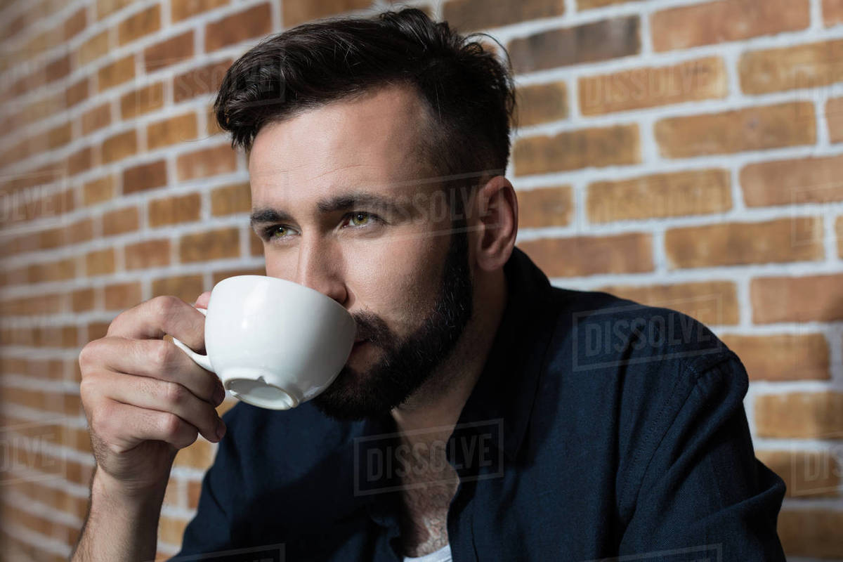 Handsome bearded young man drinking coffee at morning - Stock Photo ...