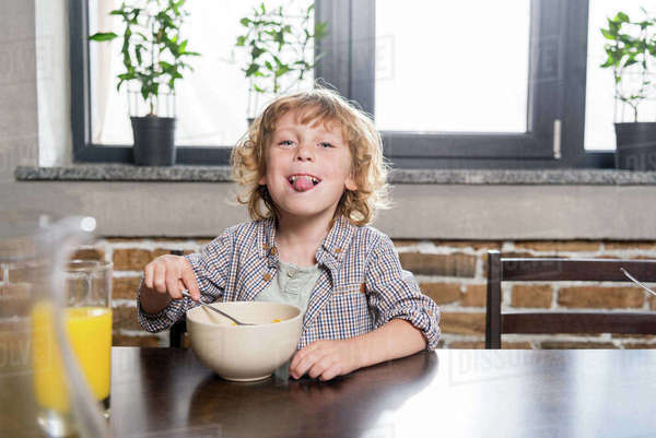 Adorable little boy eating breakfast and smiling at camera - Royalty ...