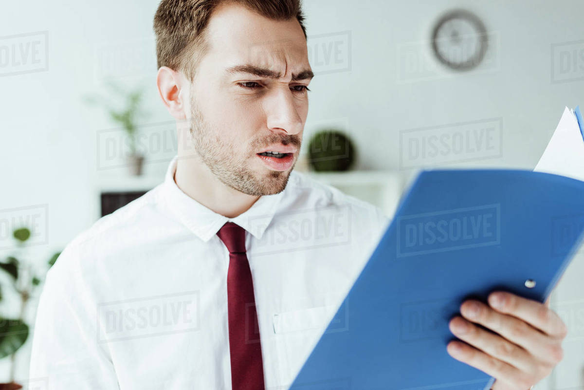 Confused businessman holding folder and looking at documents - Royalty ...