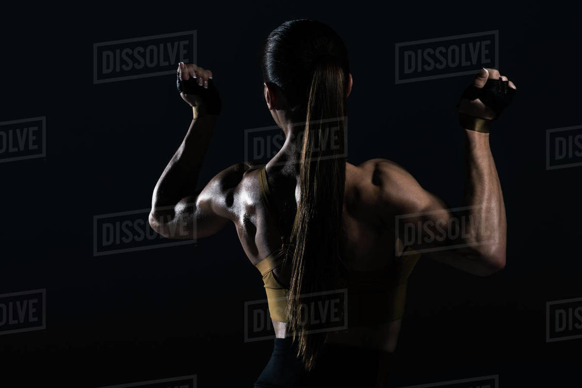Back view of strong female bodybuilder posing and showing muscles ...