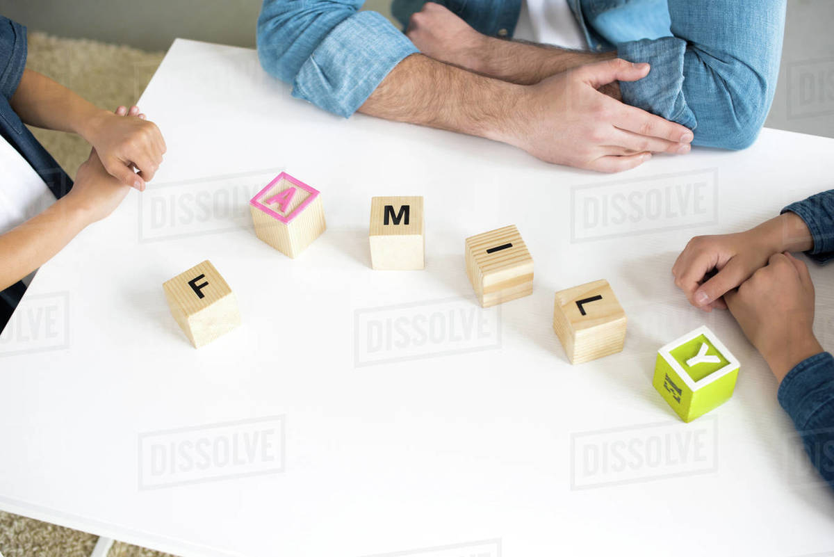 Close-up view of cubes with word family and hands of father with kids ...