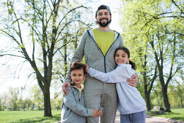 Happy little children embracing father in park - Royalty-free Stock ...