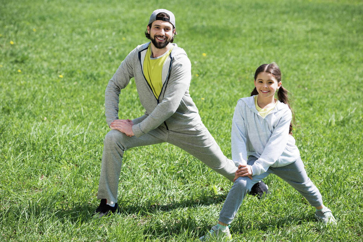 Father and daughter doing physical exercise on meadow in park - Royalty ...