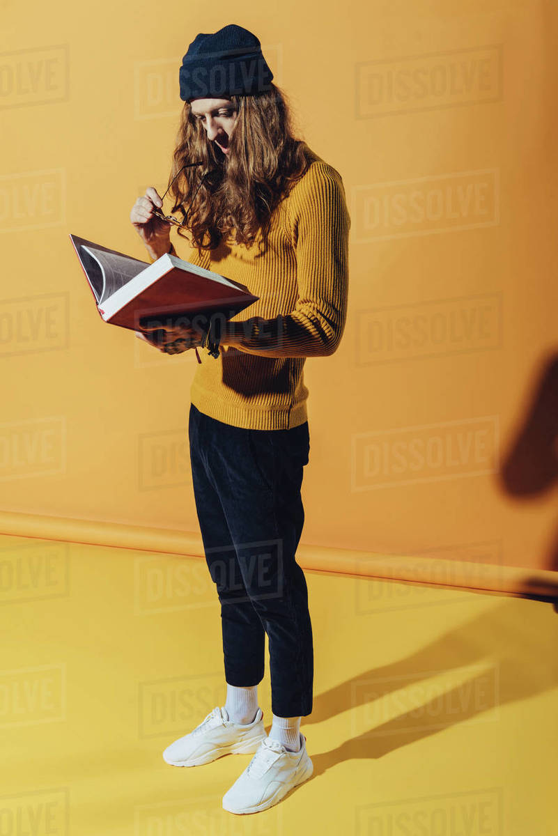 Elegant man with long hair reading book, on yellow - Royalty-free Stock ...