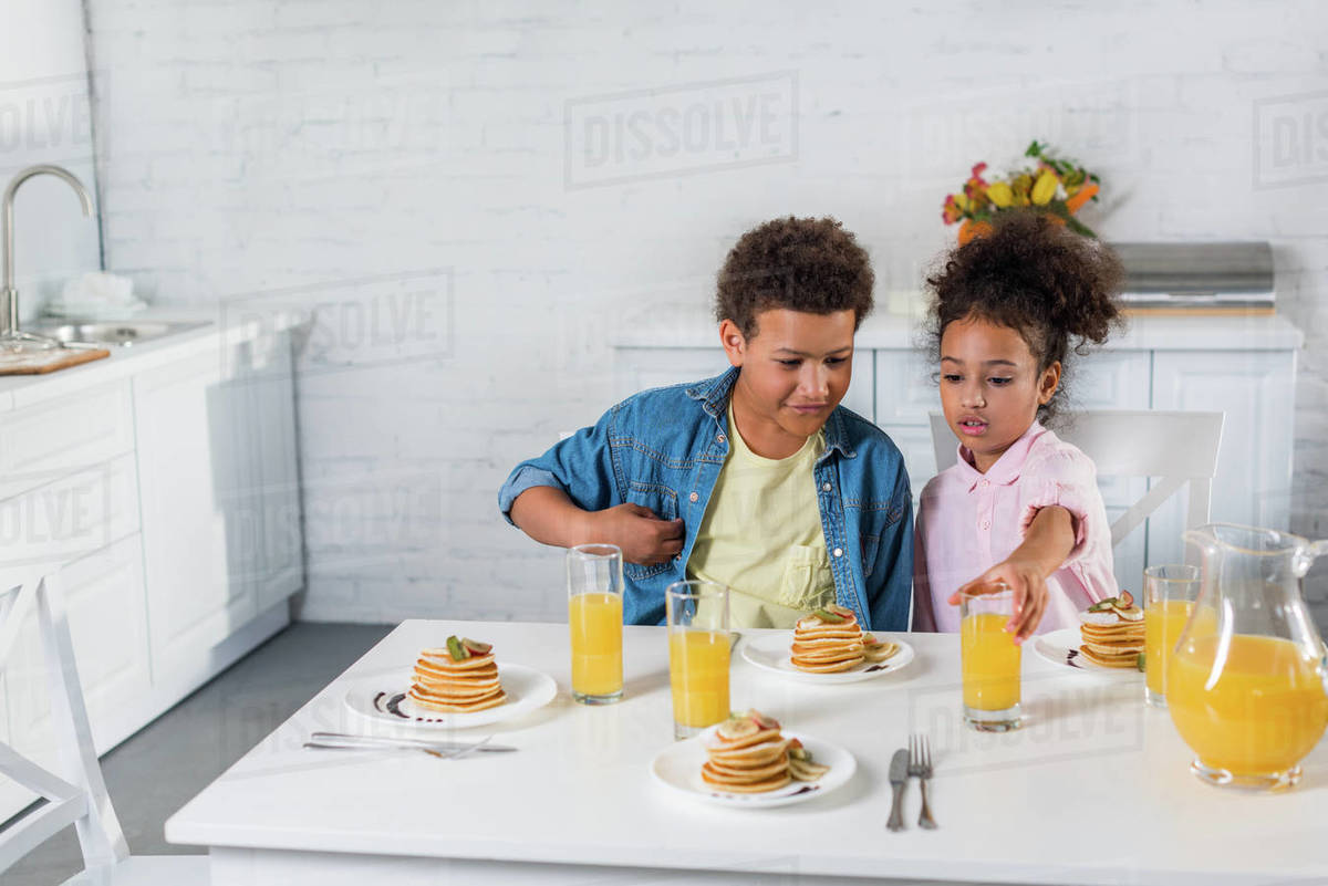 African american brother and sister eating breakfast with pancakes ...